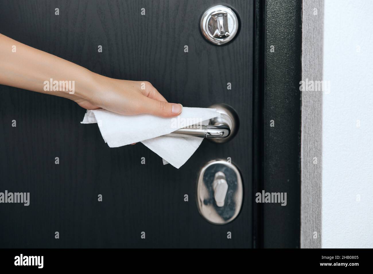 Cleaning black door handles with an antiseptic wet wipe. Woman hand ...