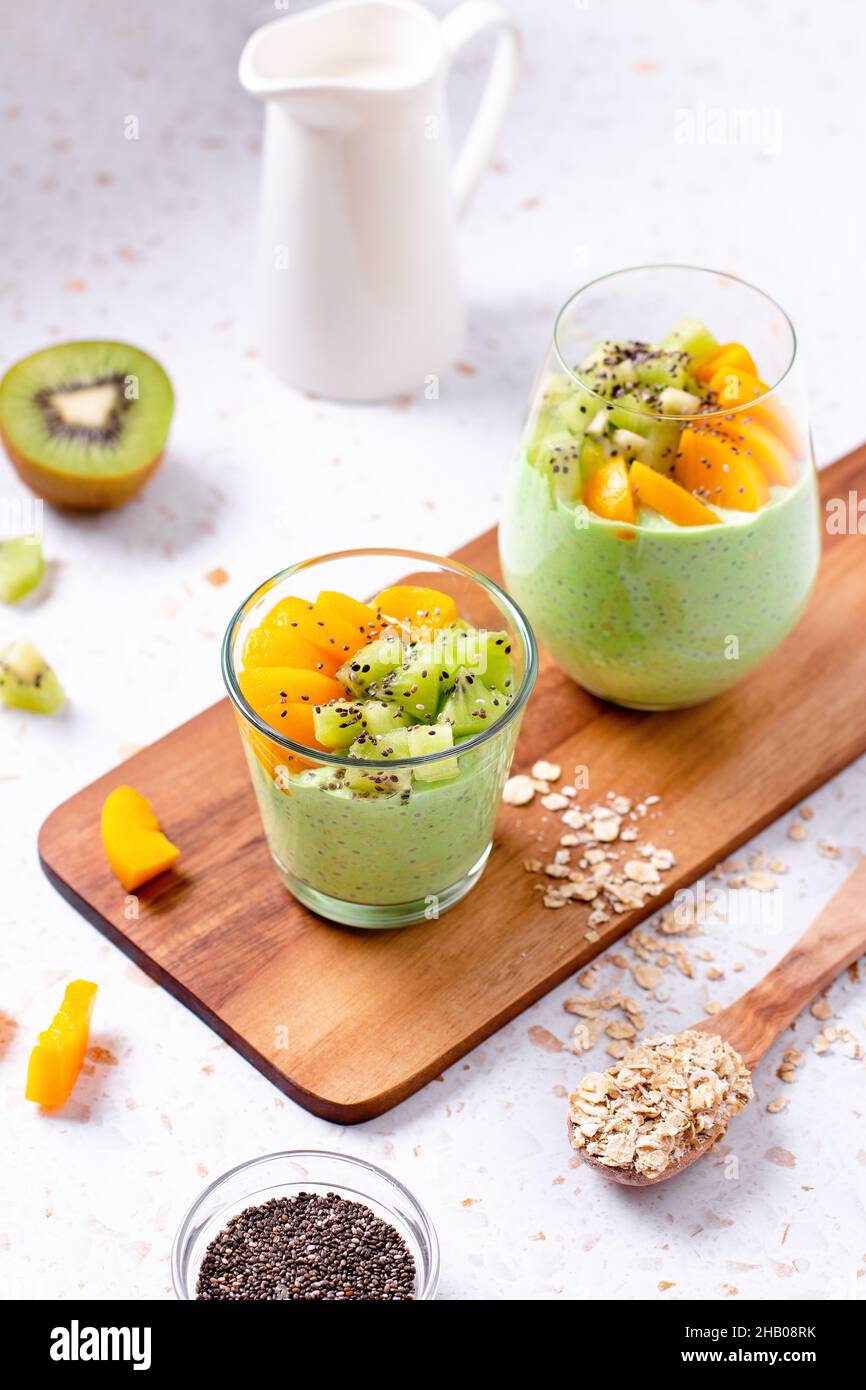 Matcha overnight oats with kiwi and peach fruits, chia seeds in glass ...