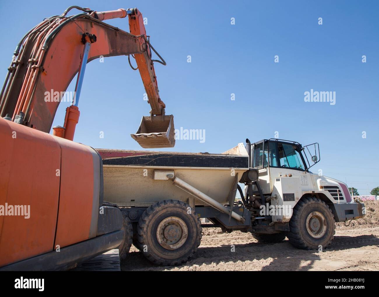 orange tracked excavator and an articulated construction dumper during ...