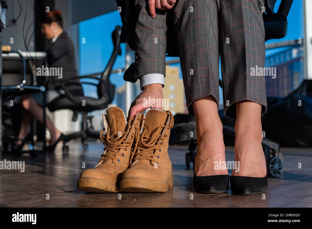 Business woman changes shoes with high heels on boots in the office ...