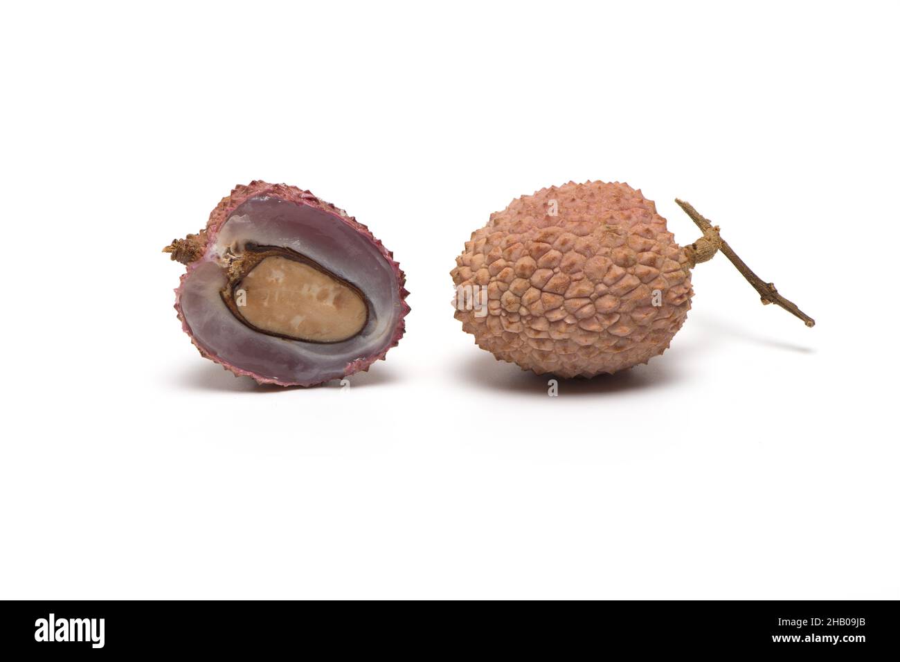 a ripe lychee next to a cut lychee half showing the inside isolated on ...