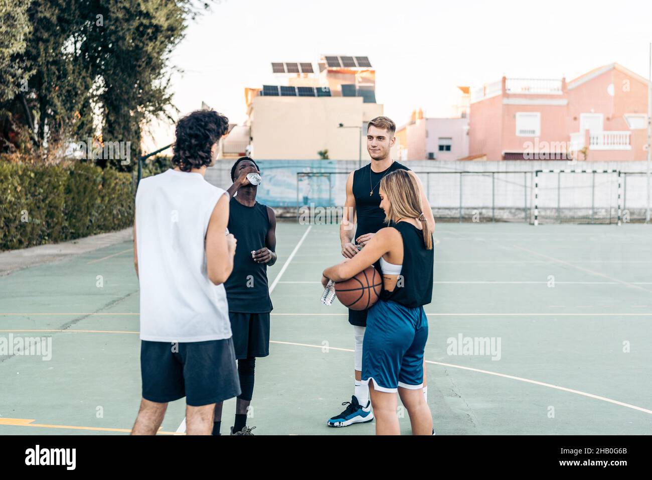 Friends standing with a basketball in a outdoor court Stock Photo - Alamy