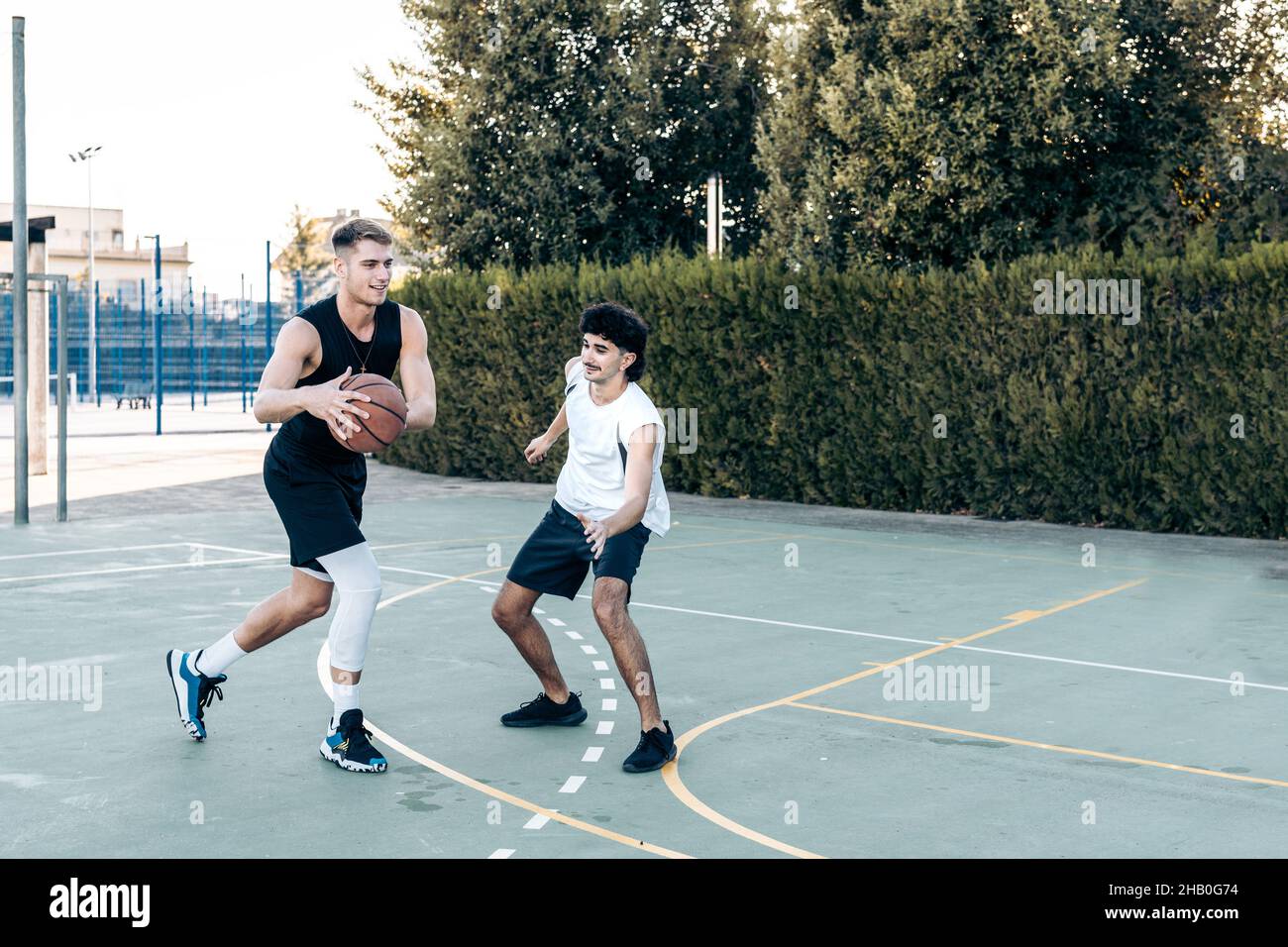 Two caucasian man playing basketball in a urban court Stock Photo - Alamy
