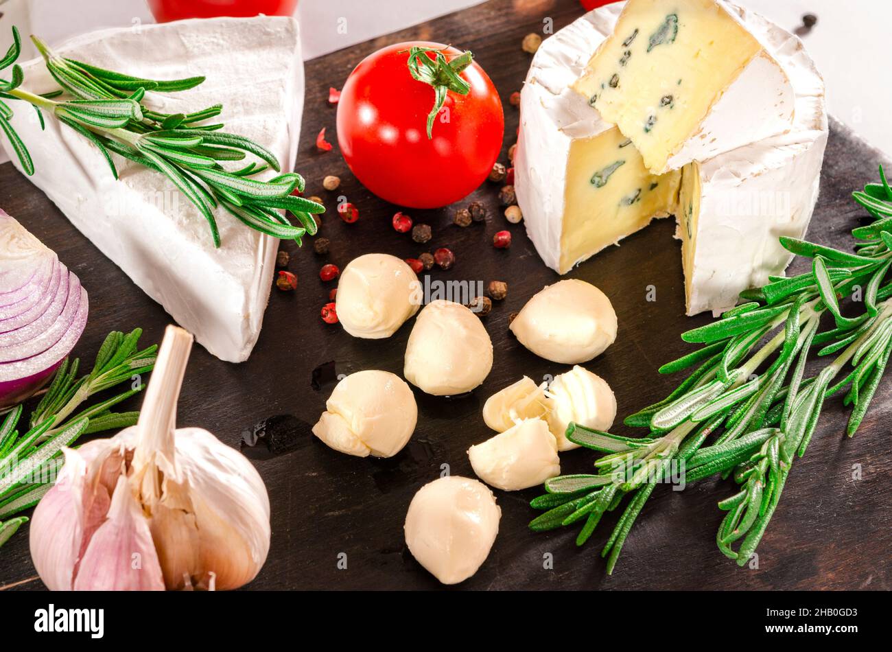 Cheese and tomatoes on wooden desk. Close-up shoot. Assorted cheeses on ...