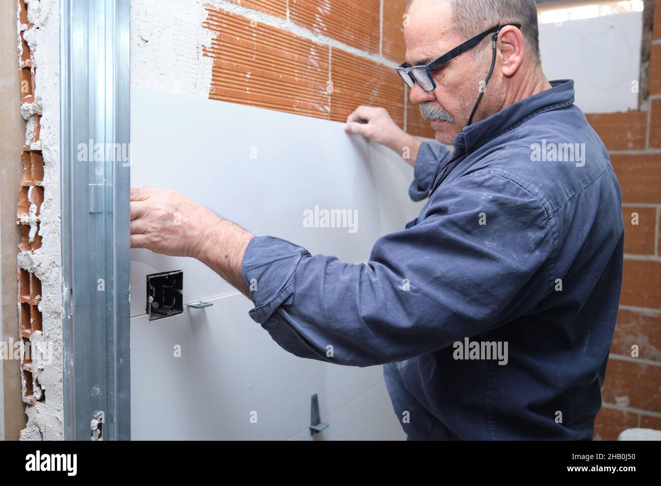 Professional tiler placing white ceramic tiles on the wall Stock Photo ...