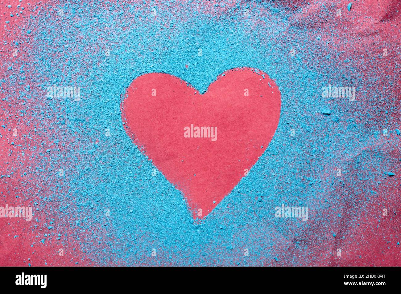Valentine's Day. Red heart - a symbol of love sprinkled with bright blue powder, on a bright ...
