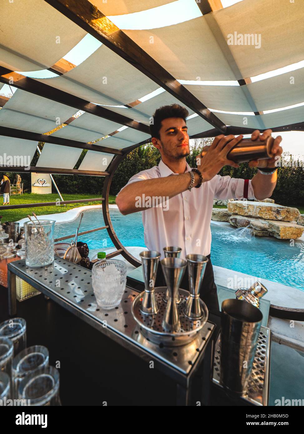 Young attractive Caucasian barman shaking a cocktail at an outdoor ...