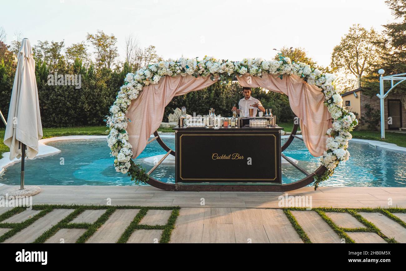 Young attractive Caucasian barman shaking a cocktail at an outdoor ...