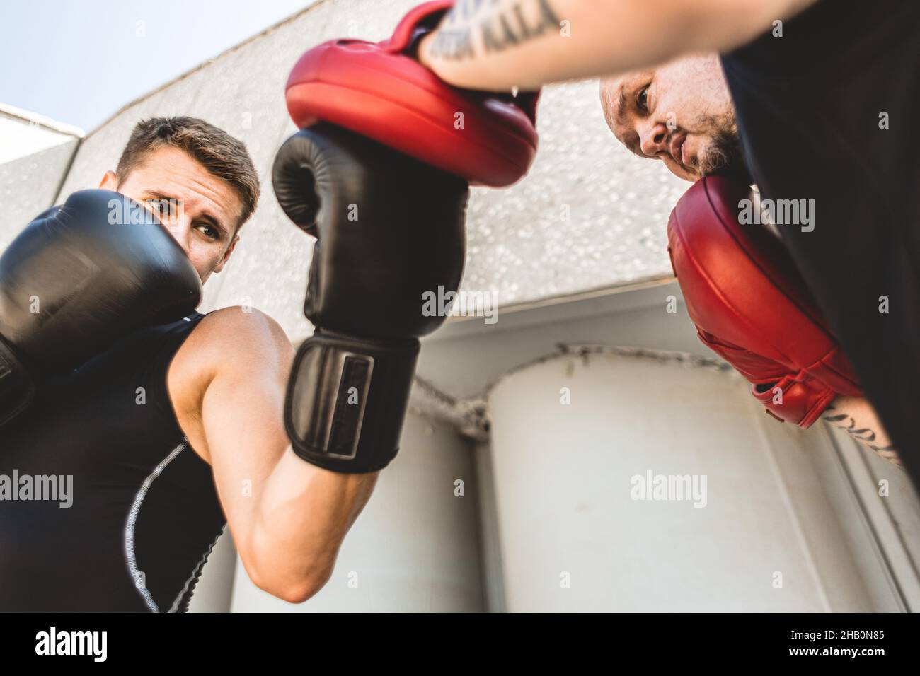 Two men exercising and fighting in outside. Boxer in gloves is training ...