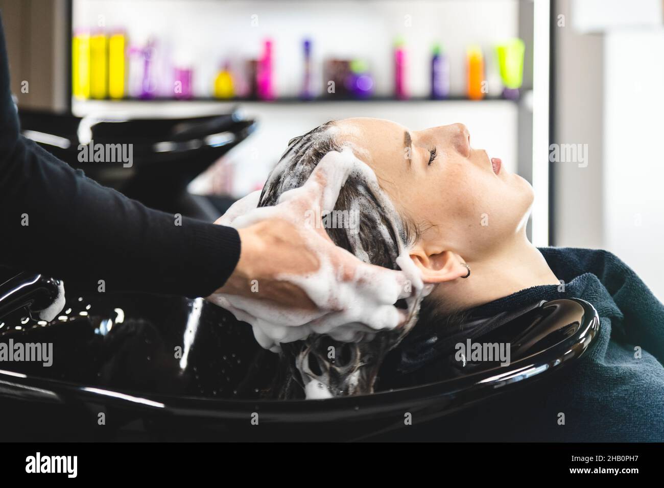 Master woman hairdresser gently washes the girl's hair with shampoo and ...