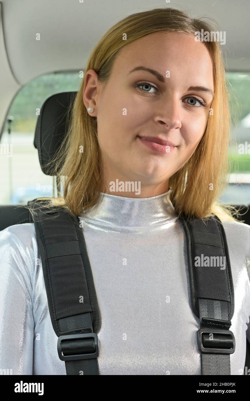 Young Woman Wearing A Catsuit Sitting In A Car Buckled Up In A Harness