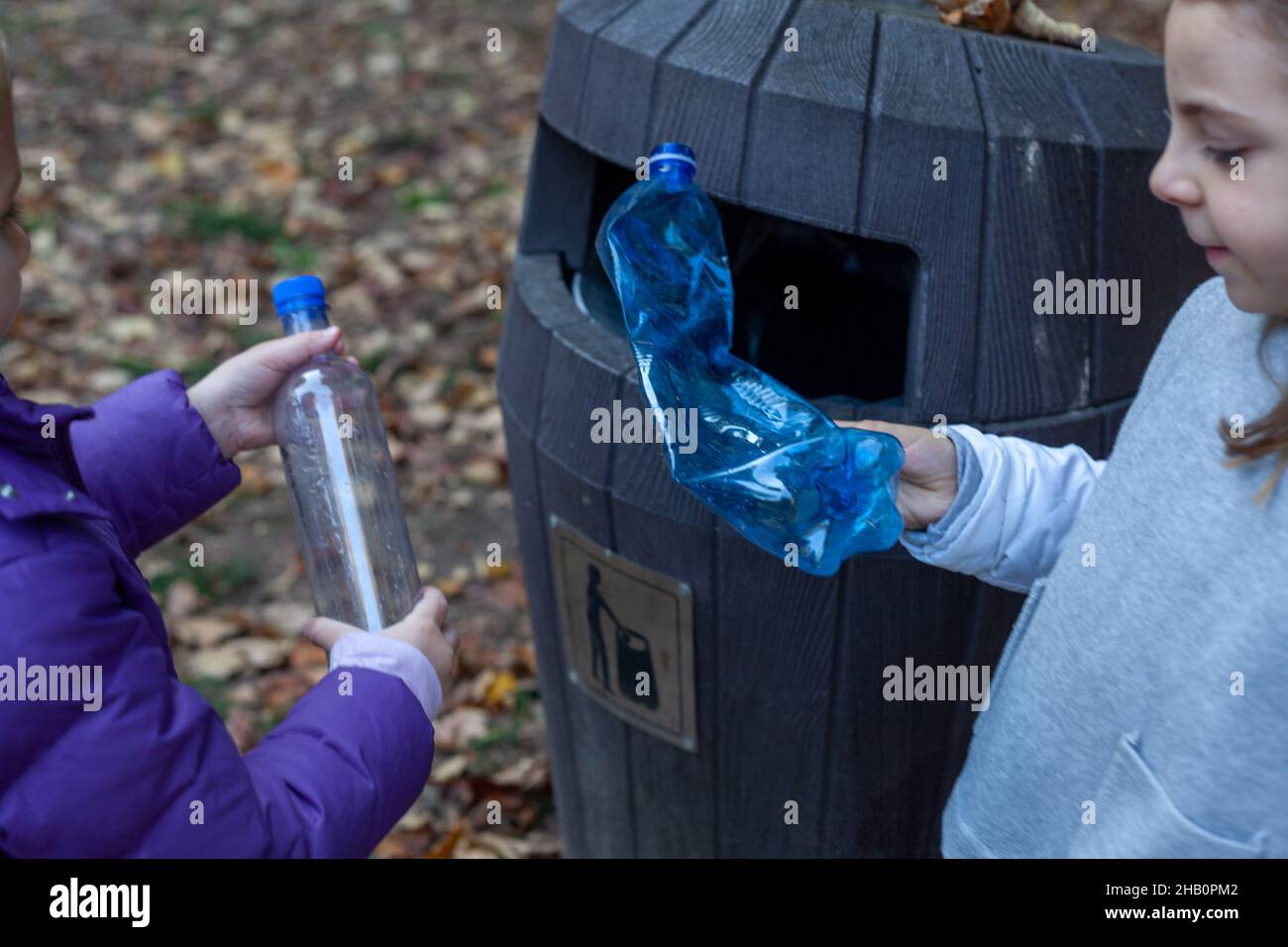 Little kids throwing plastic into a recycle bin Stock Photo - Alamy