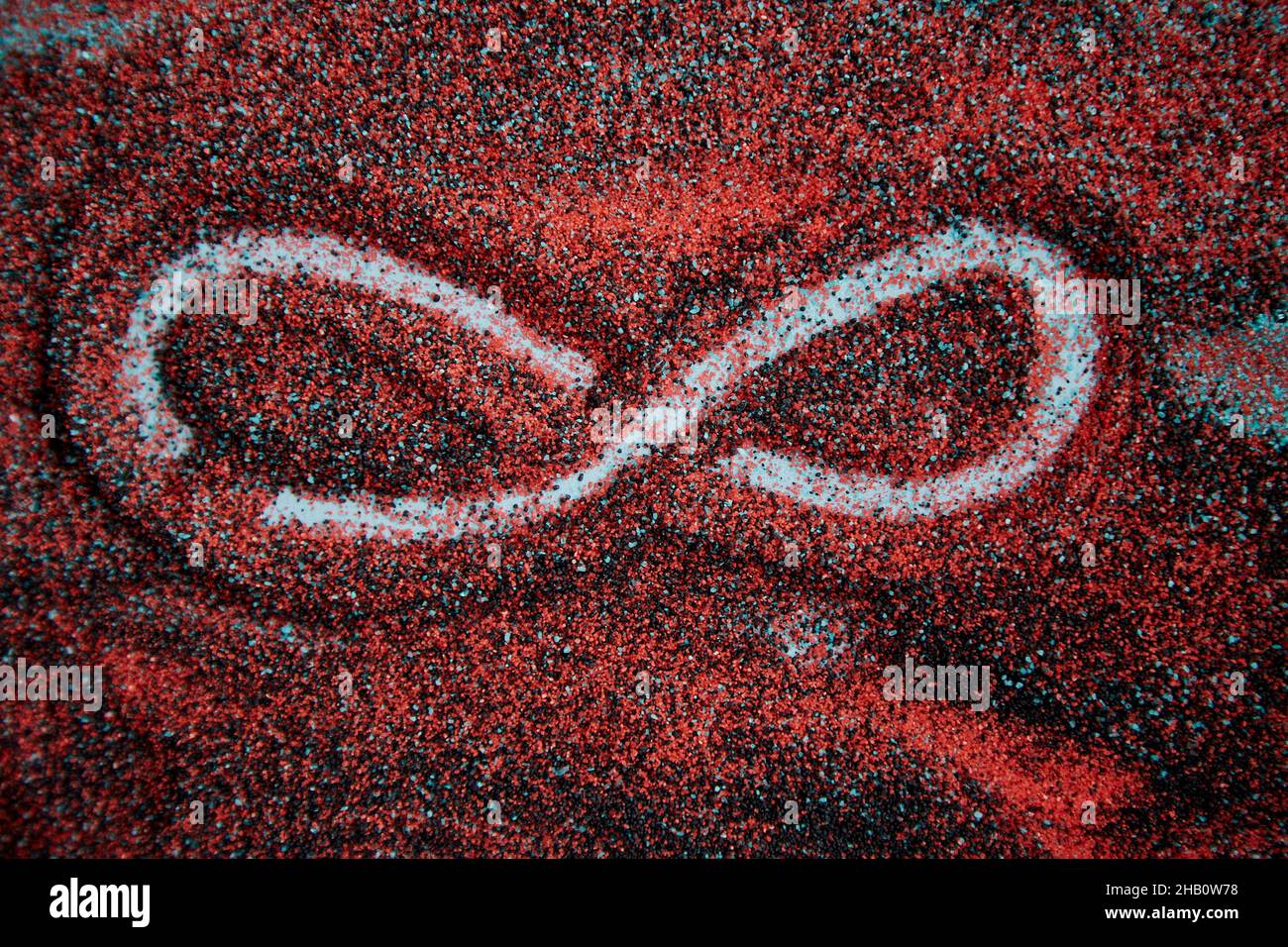 Creative infinity symbol on bright red and black sand background ...