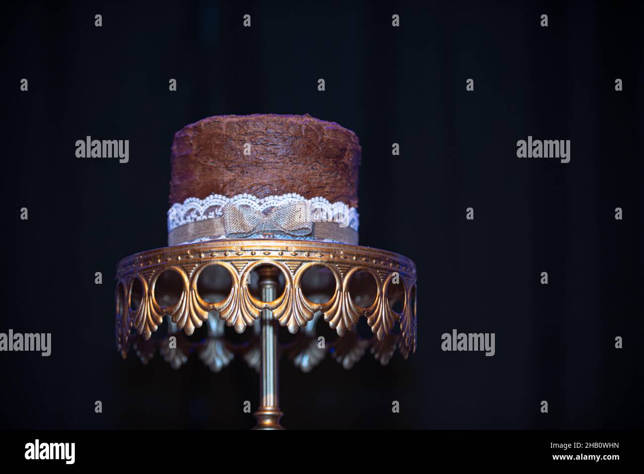 Chocolate one tier wedding cake with lace decoration and bows on gold ...