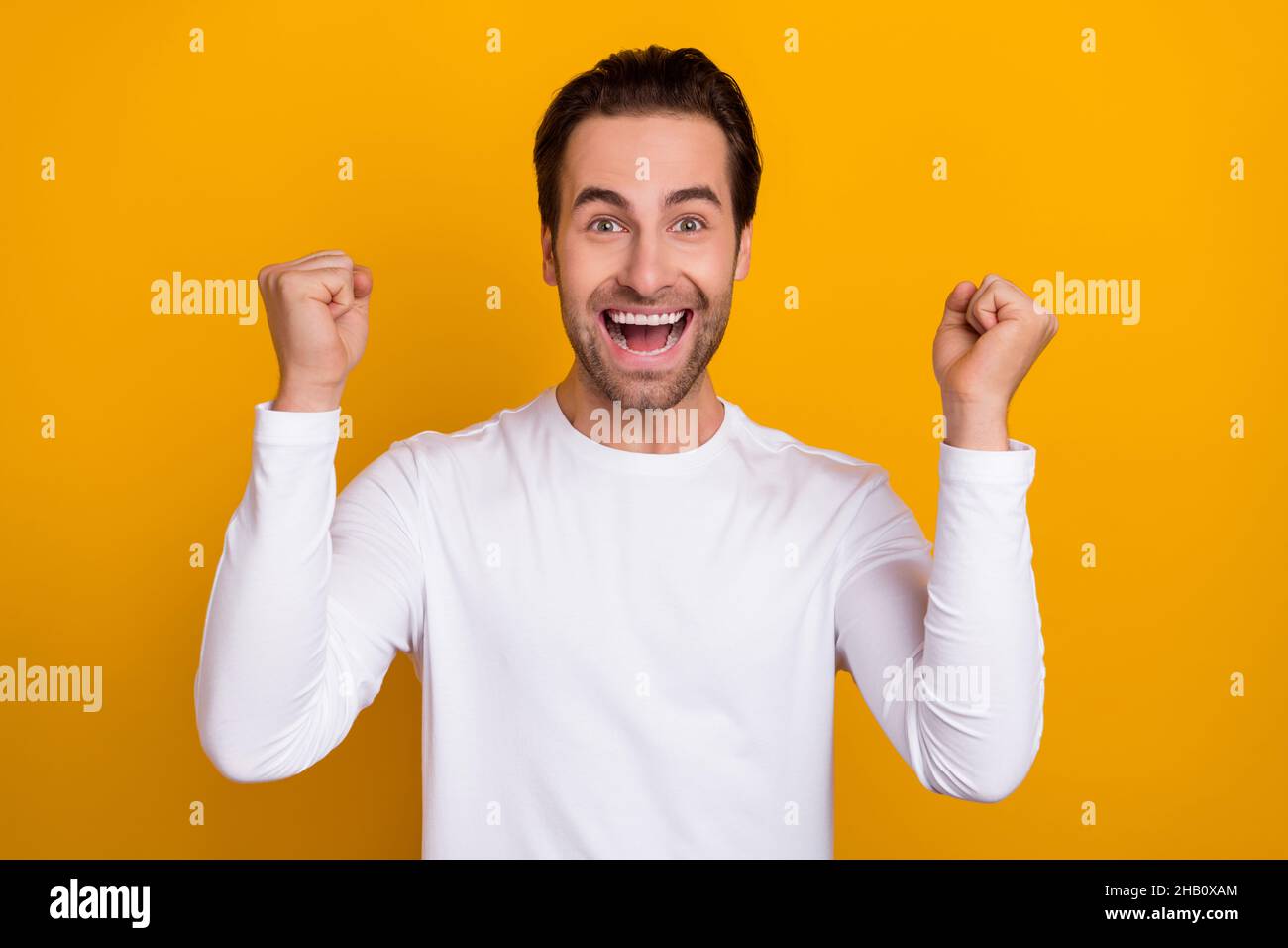 Portrait of positive ecstatic man raise fists scream yeah celebrate ...