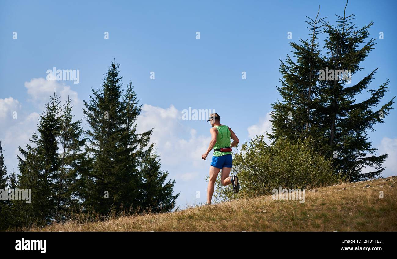 Back view of man athlete jogging outdoors. Young sportsman in sporty ...