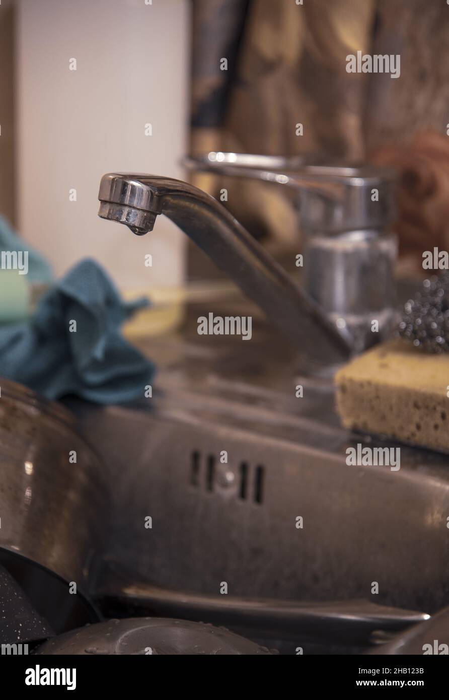 The water tap over the kitchen sink with dirty dishes. Focus on the ...