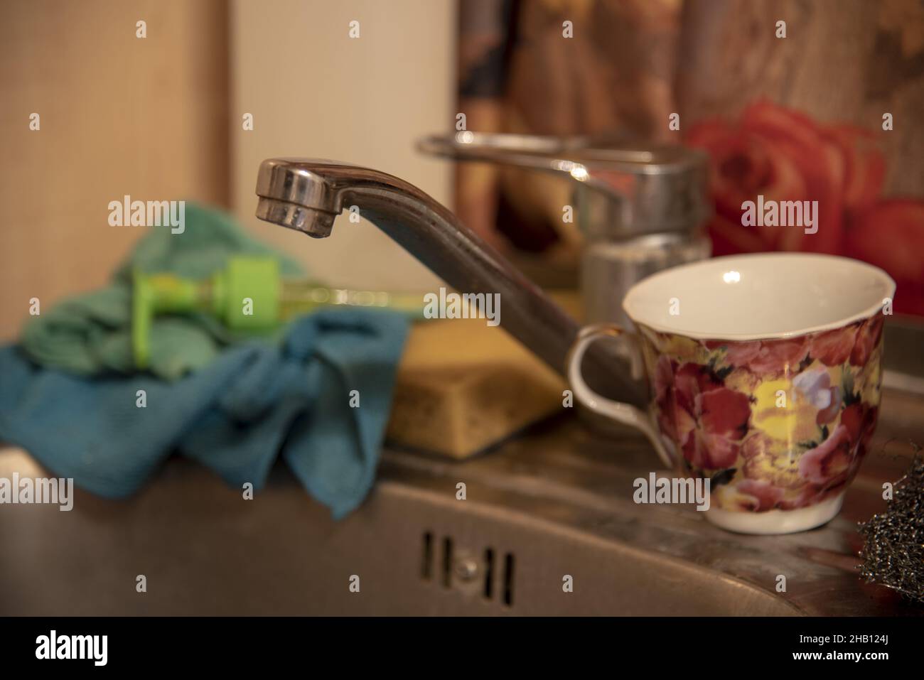 The water tap over the kitchen sink with dirty dishes. Focus on the ...