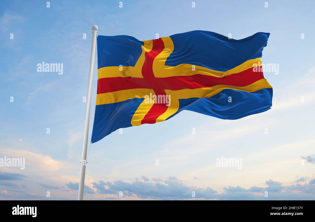 official flag of Aland Islands at cloudy sky background on sunset ...