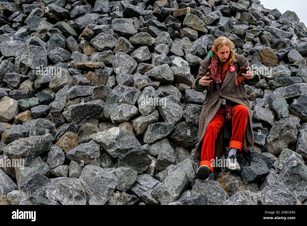 Berlin, Germany. Young adult punk dude sitting on a pile of rock near a ...