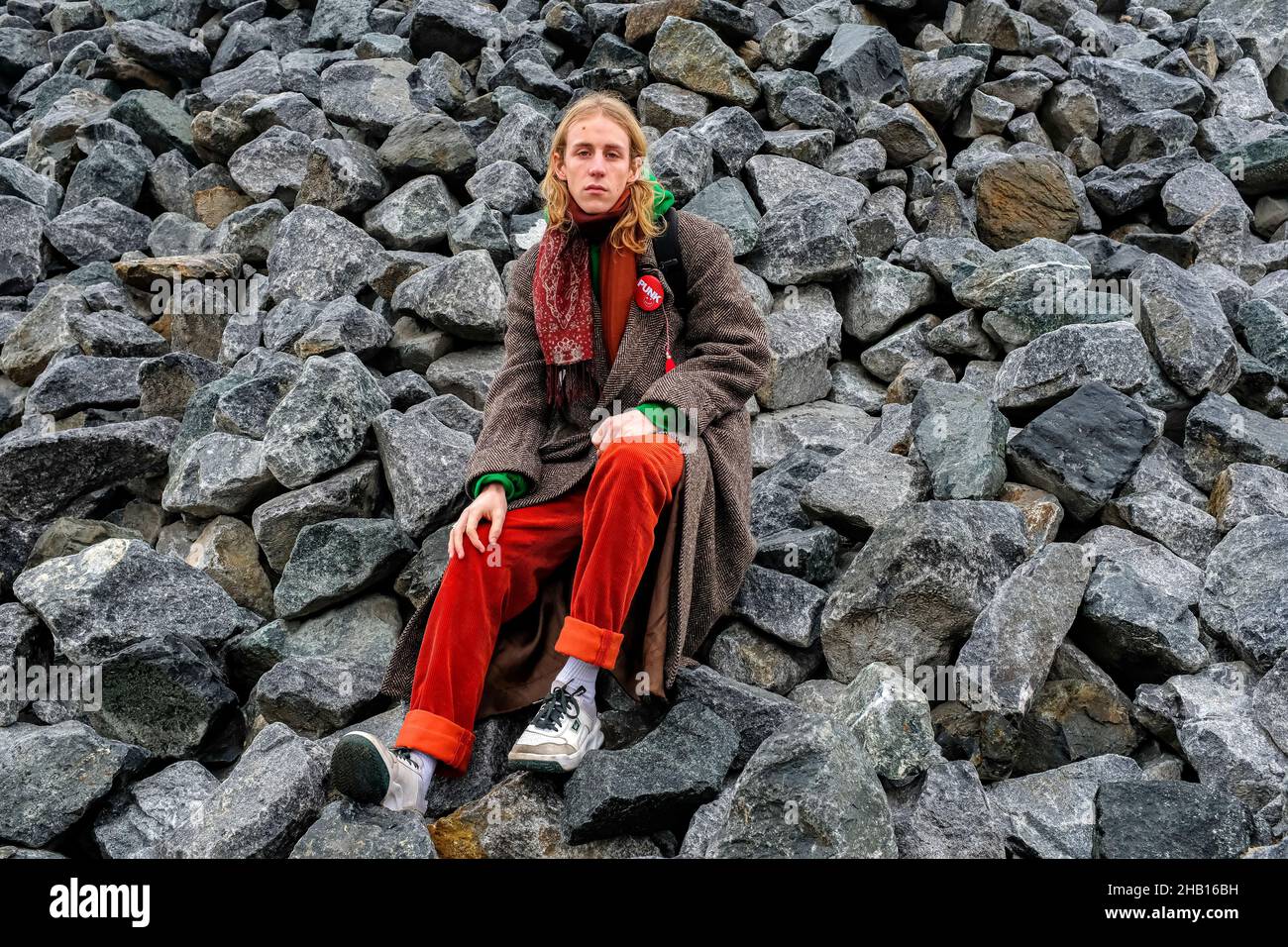 Berlin, Germany. Young adult punk dude, named: Leonard Wellington, sitting on a pile of rock ...