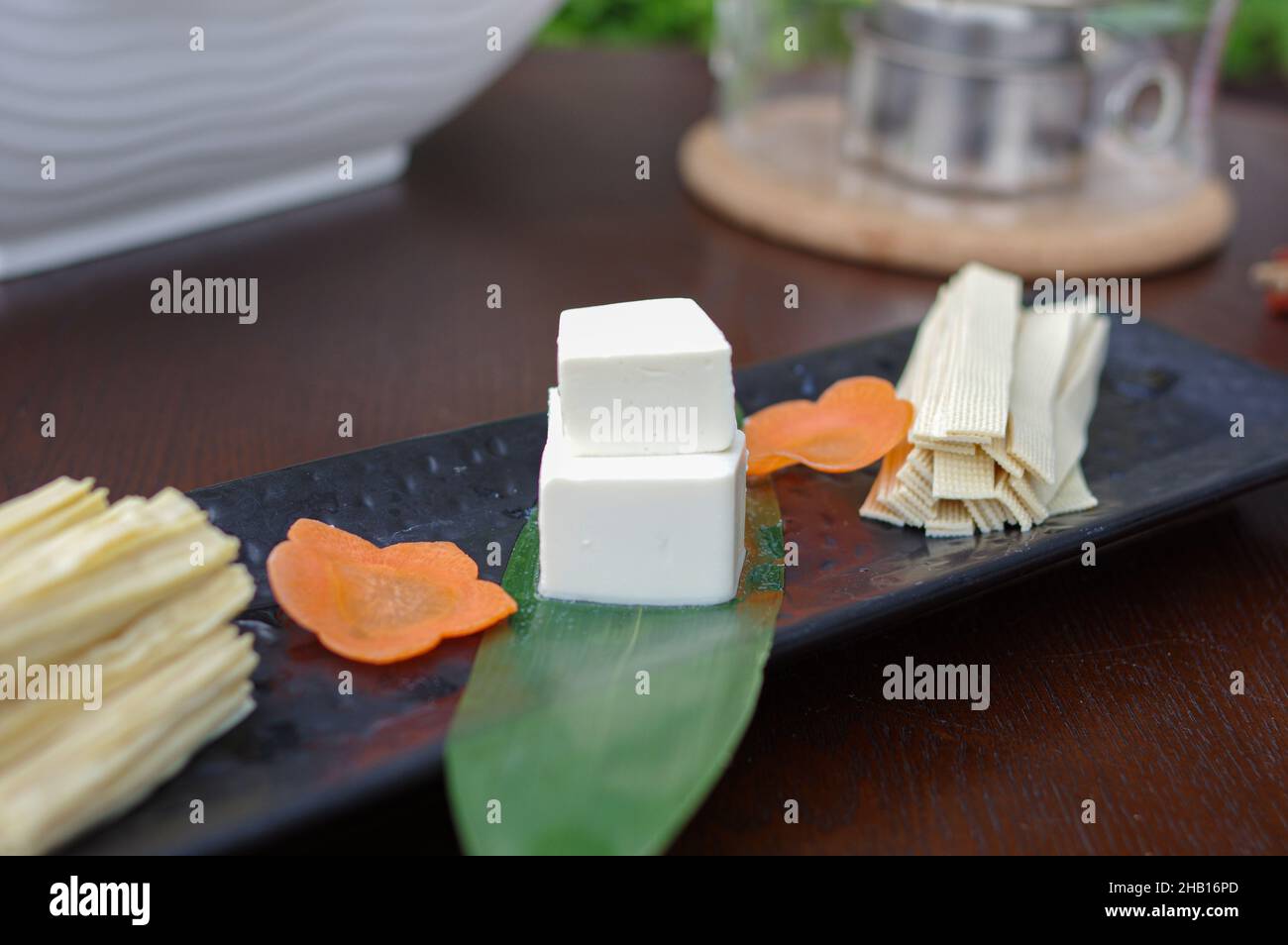 Tofu skin bean curd with carrot and bamboo leaf on black plate for hot ...