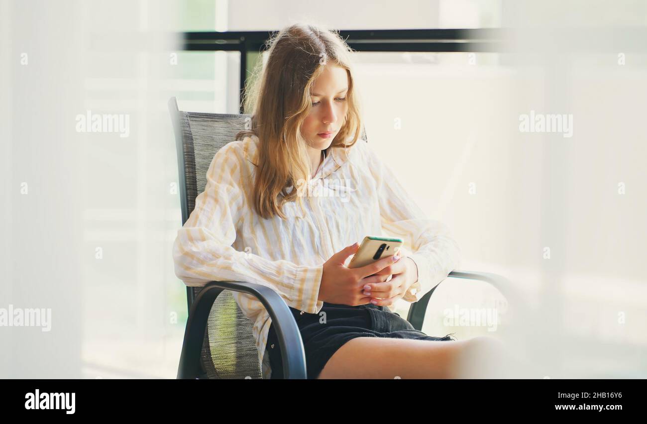 Tween girl with smartphone sitting on balcony Stock Photo - Alamy