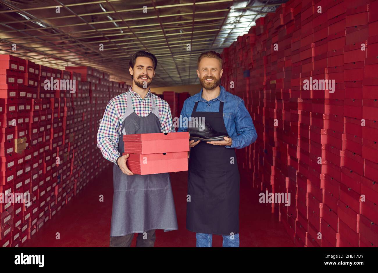 Happy shoe factory workers standing in warehouse, holding boxes and ...