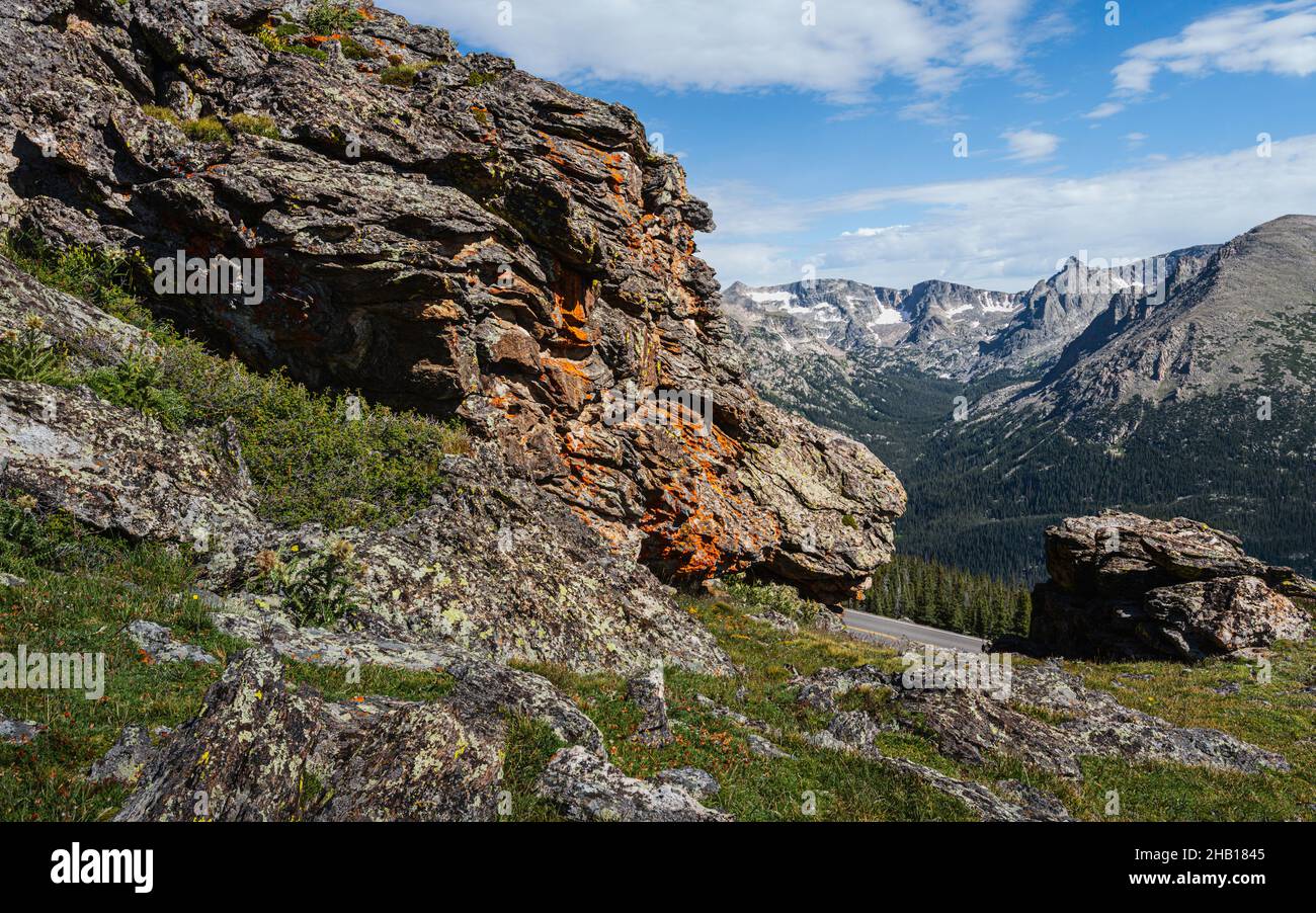 The Rocky Mountains outcrop with rocks and grasses under bright blue ...