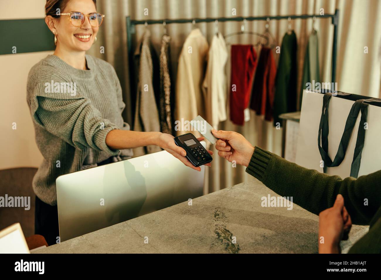 Friendly store assistant taking a card payment from a female customer ...