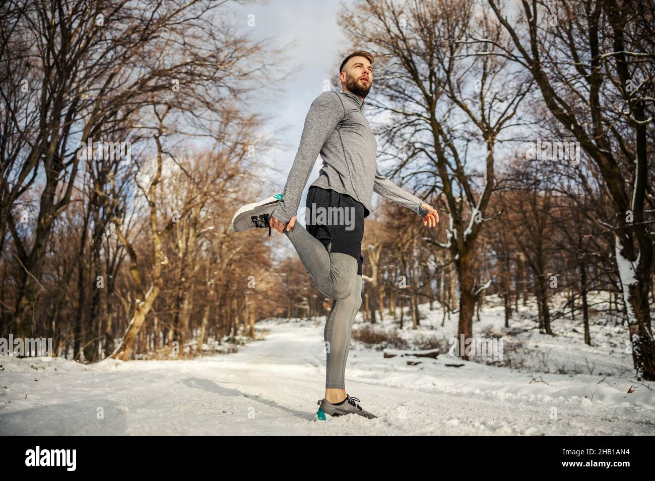 Runner doing warm up exercises in nature at snowy winter day. Winter ...