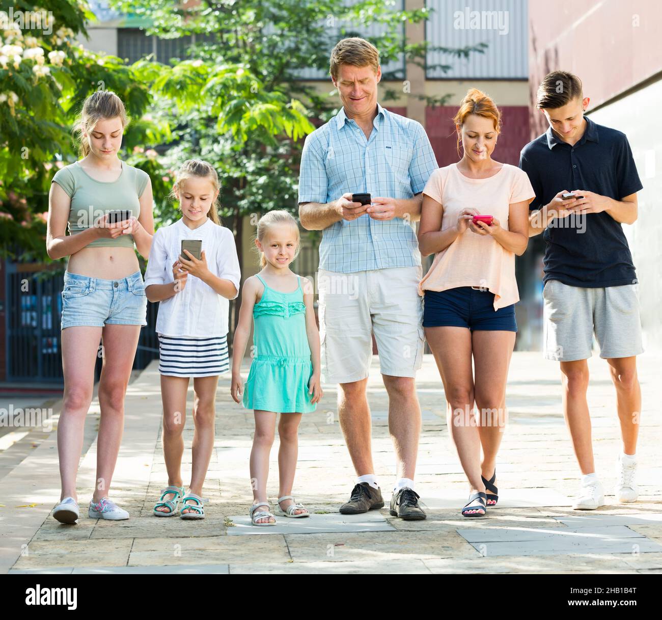 Portrait of happy large family standing with their mobile phones ...