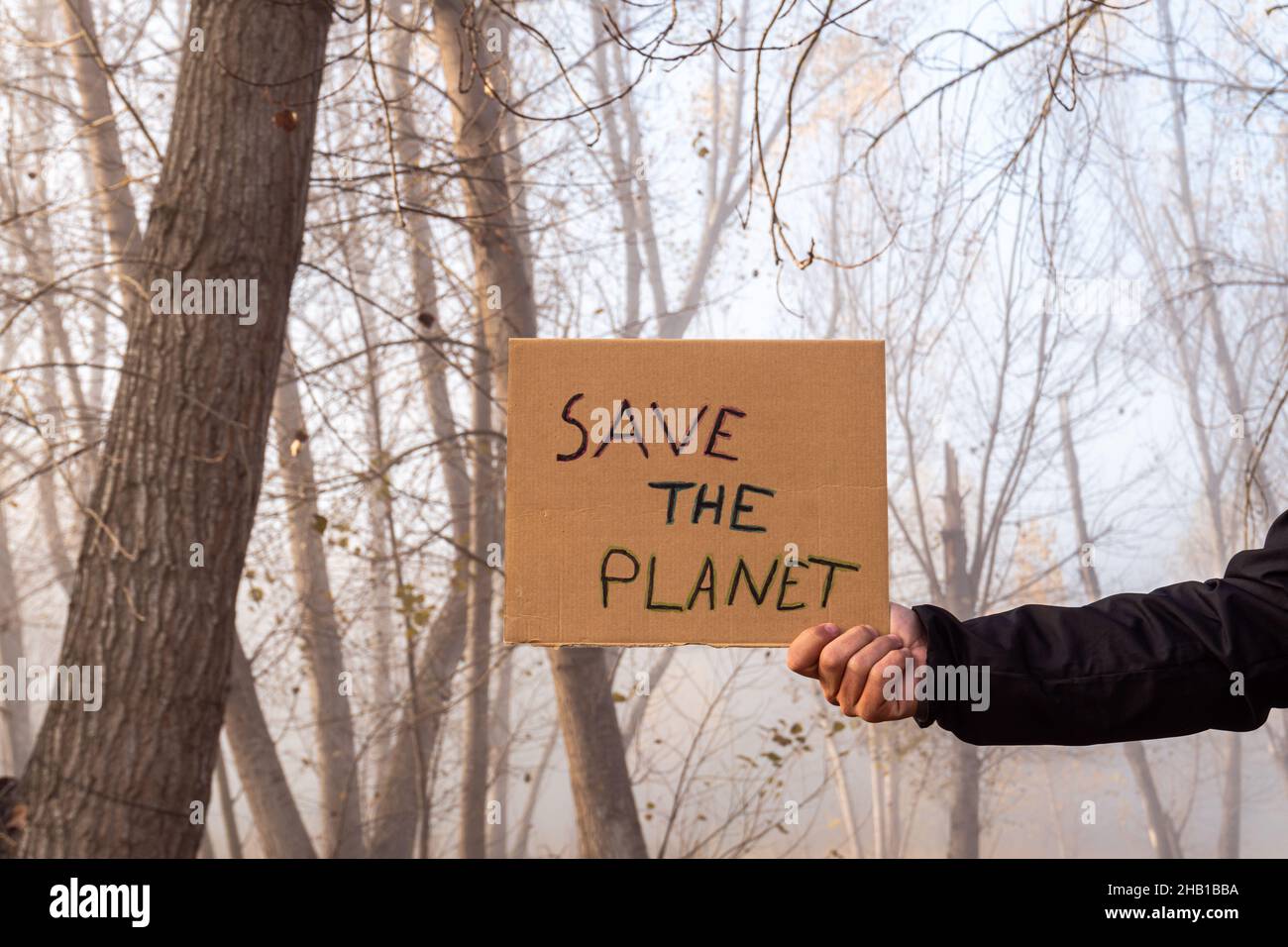 Male hands hold a cardboard sign with the slogan Save the Planet with ...