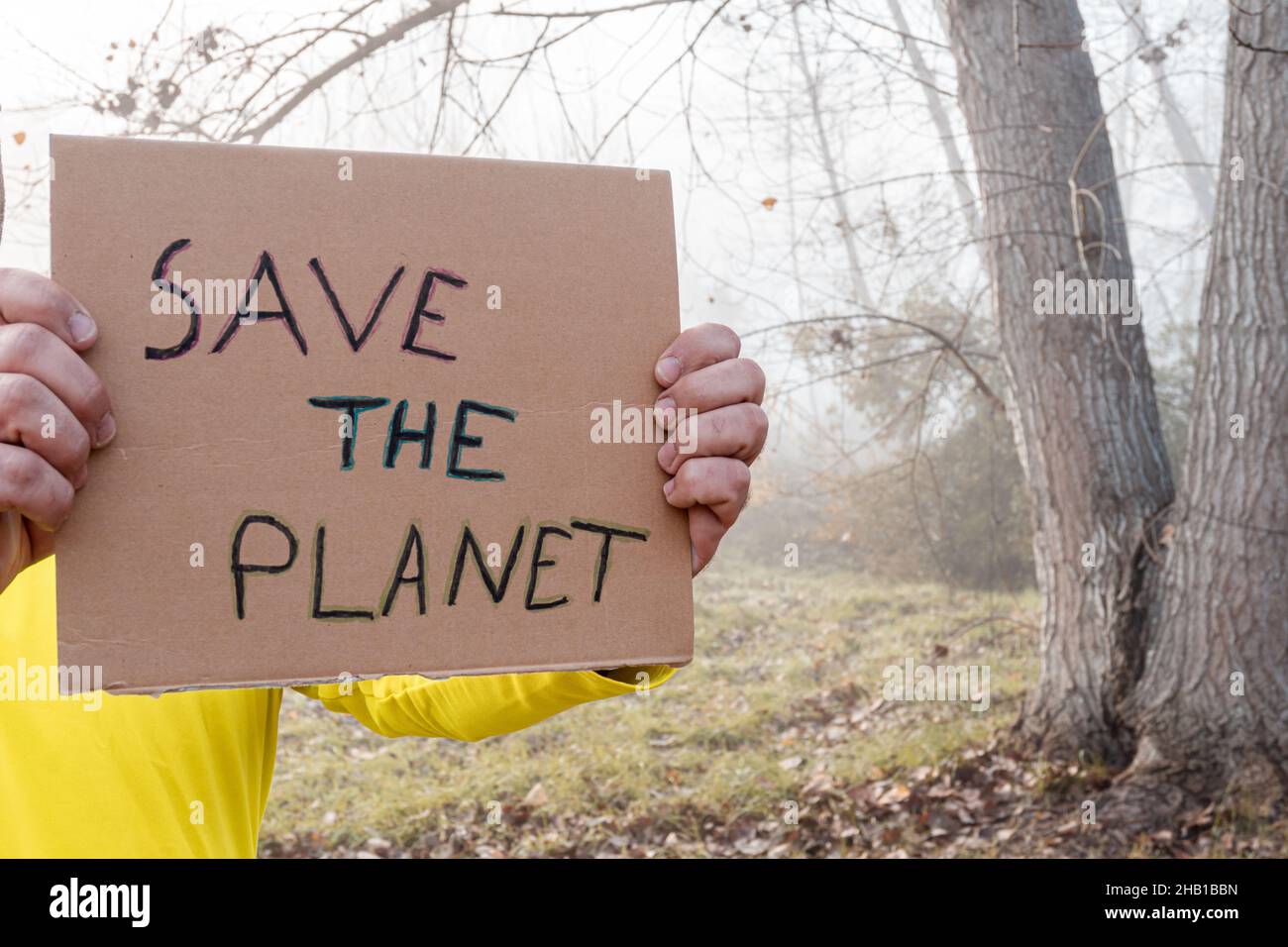 Male hands hold a cardboard sign with the slogan Save the Planet with ...