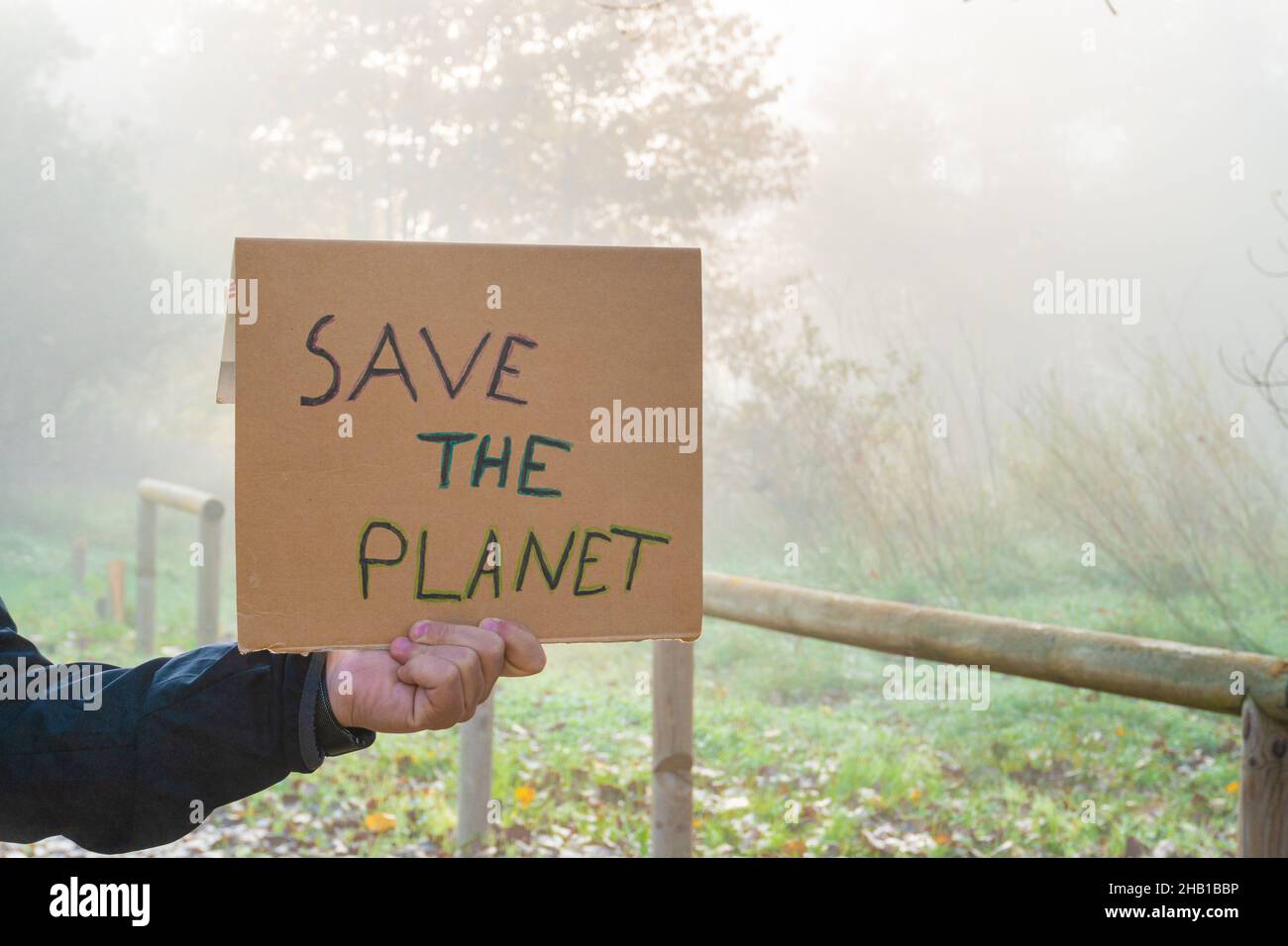 Male hands hold a cardboard sign with the slogan Save the Planet with ...