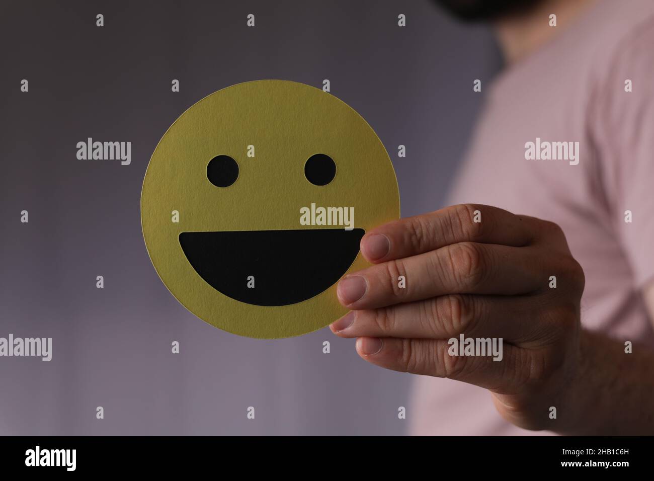 Person's hand holding a papercut emoji Stock Photo - Alamy