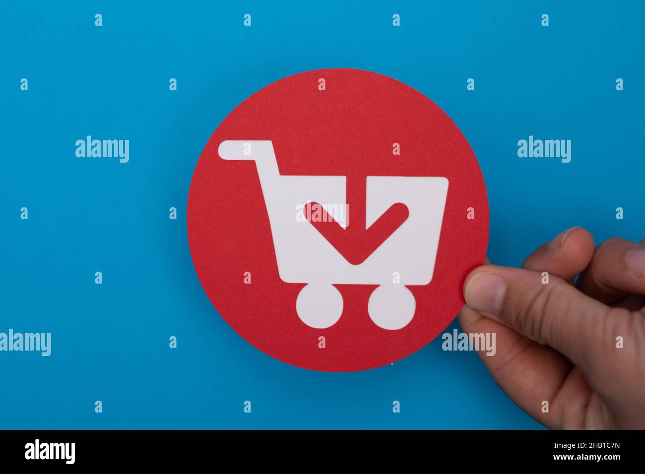 Person's hand holding a shopping cart icon Stock Photo - Alamy