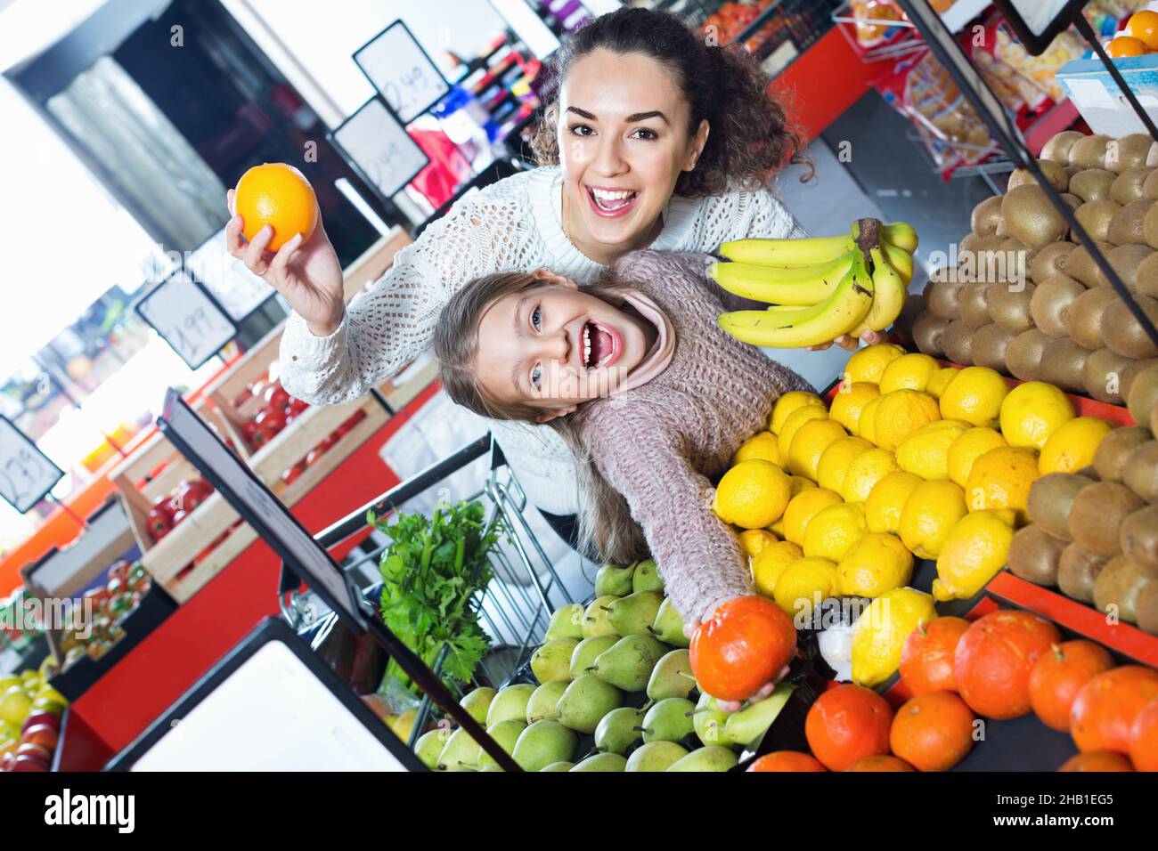 Beautiful mother and smiling little girl choosing fresh fruits Stock ...