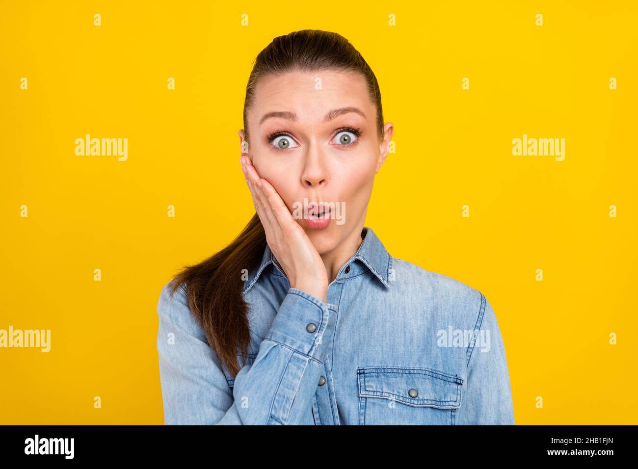 Photo of sweet shocked young lady dressed jeans shirt arm cheek ...
