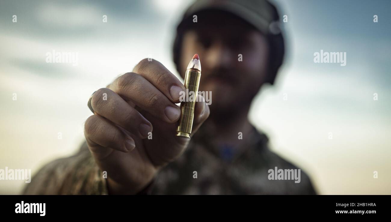 Male showing a bullet holding in his hand - hunting Stock Photo - Alamy
