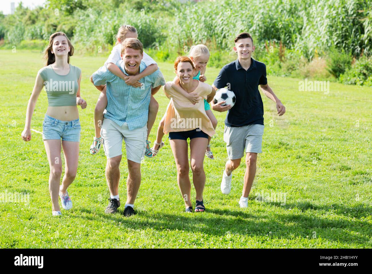 Smiling mother and father with four kids on green lawn Stock Photo - Alamy