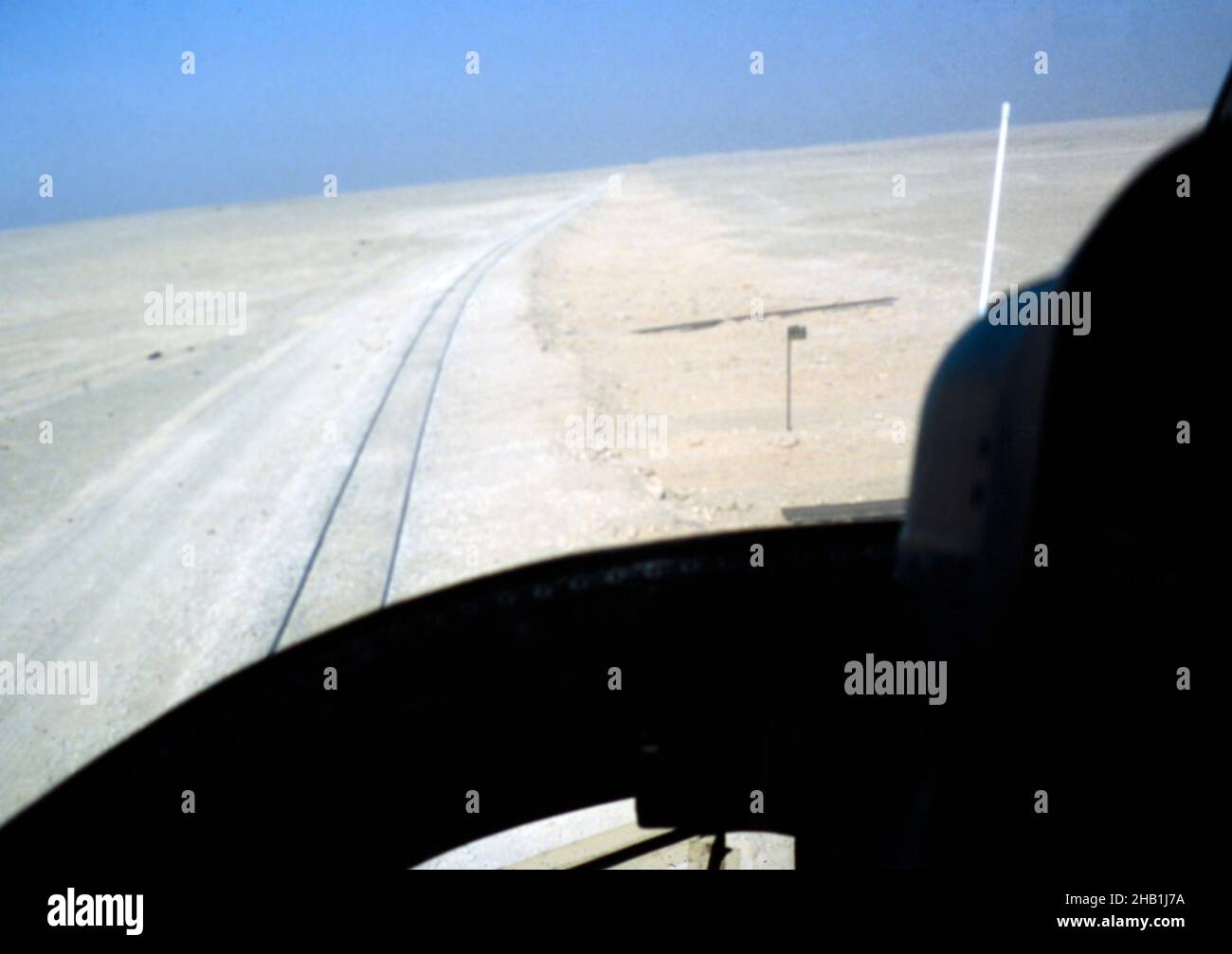 View from helicopter cockpit over railway line tracks in desert, Saudi ...