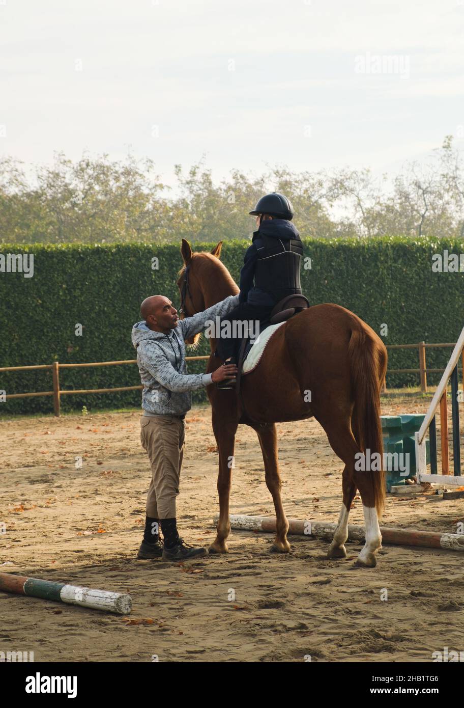 Trainer teaching kid horse back riding with obstacles Stock Photo - Alamy