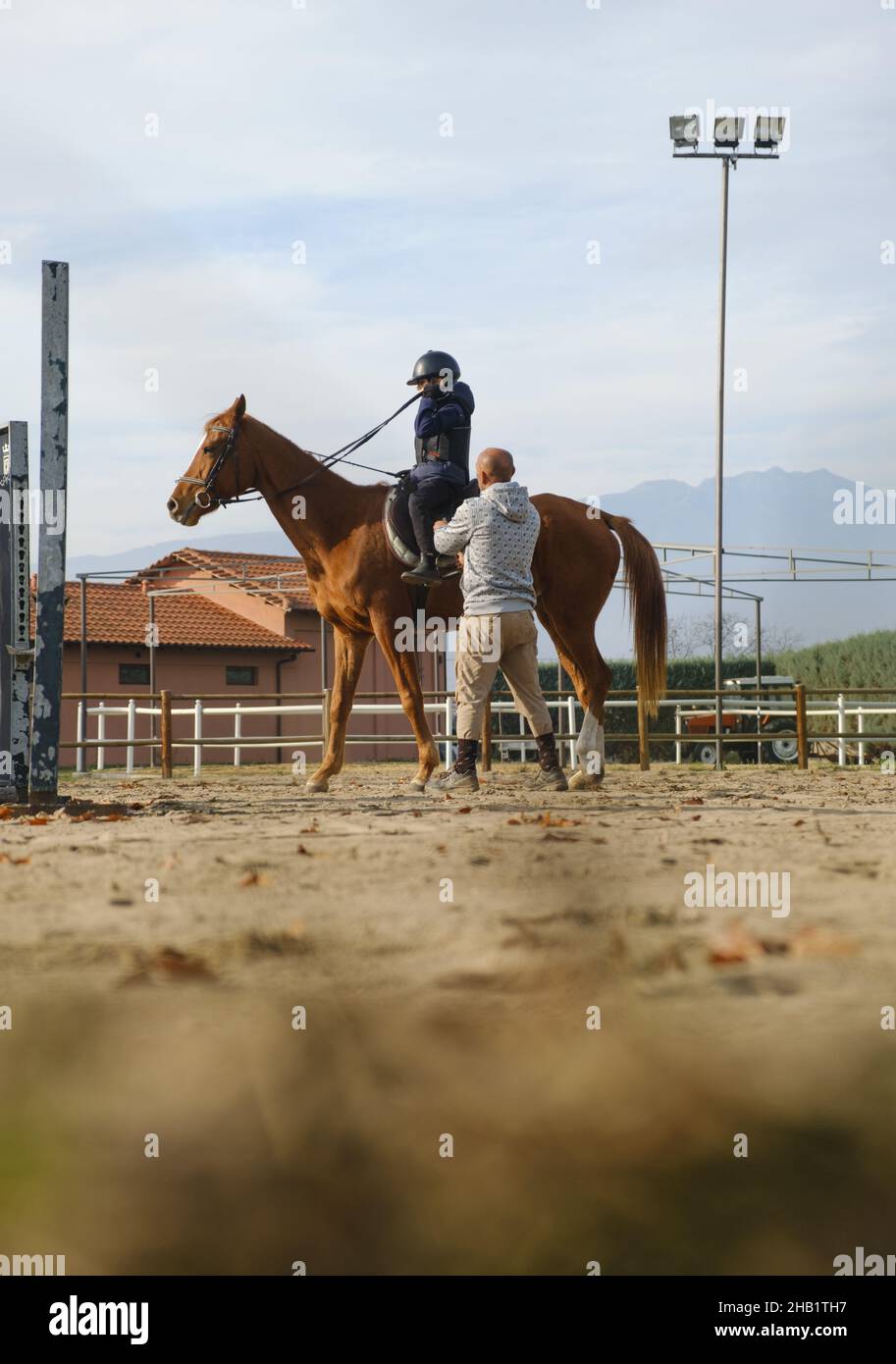 Trainer teaching kid horse back riding with obstacles Stock Photo - Alamy