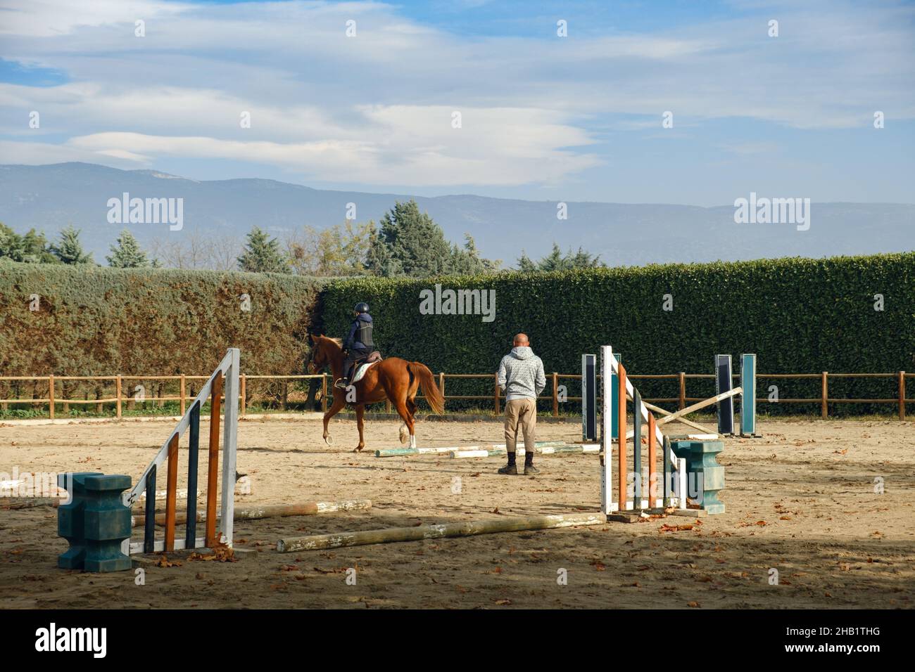 Kid learning horseback riding with obstacles at the ranch with trainer ...