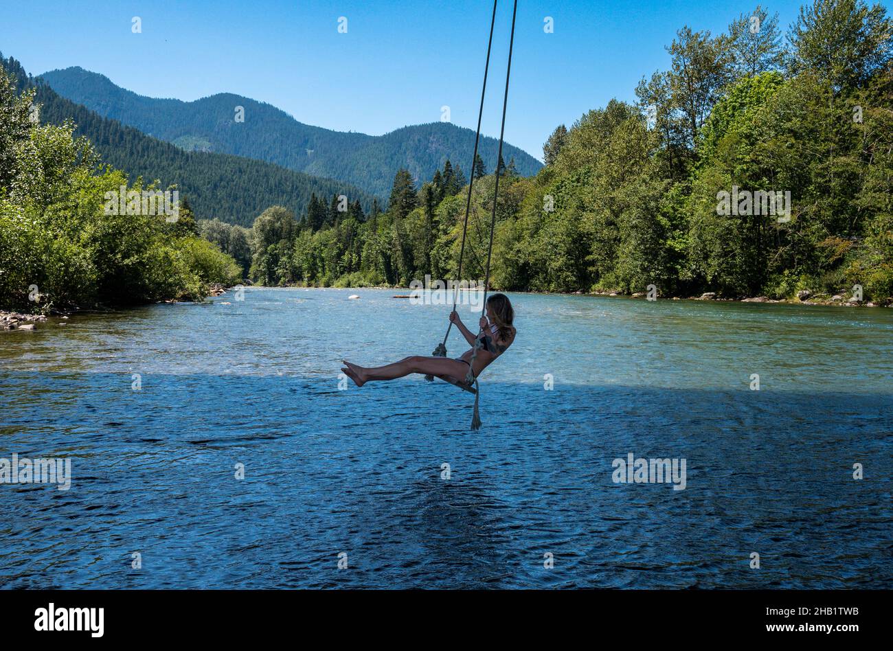 Girl in a bikini on a swing over a river in the mountains Stock Photo ...