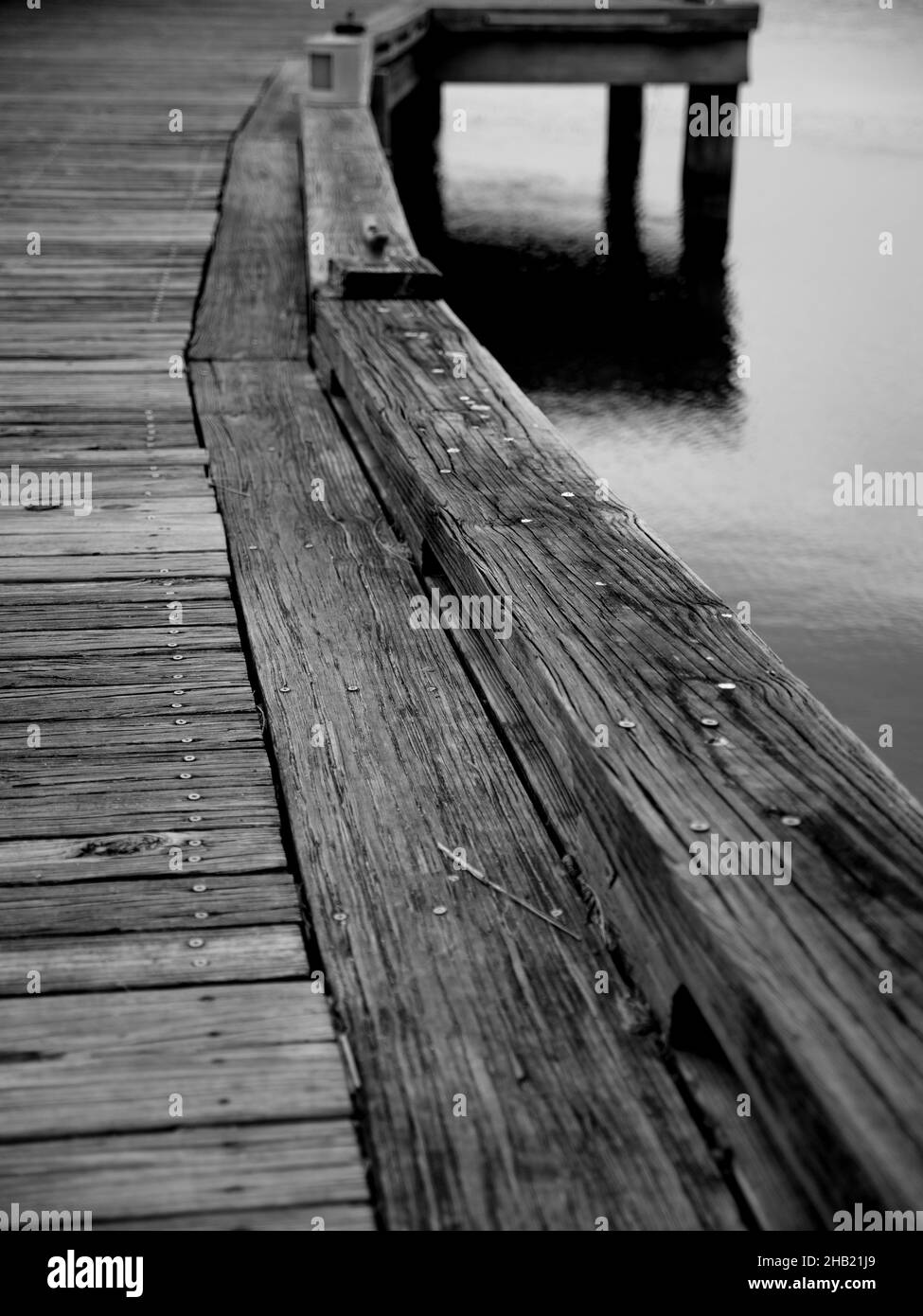 Vertical grayscale shot of a wooden dock by the sea Stock Photo - Alamy