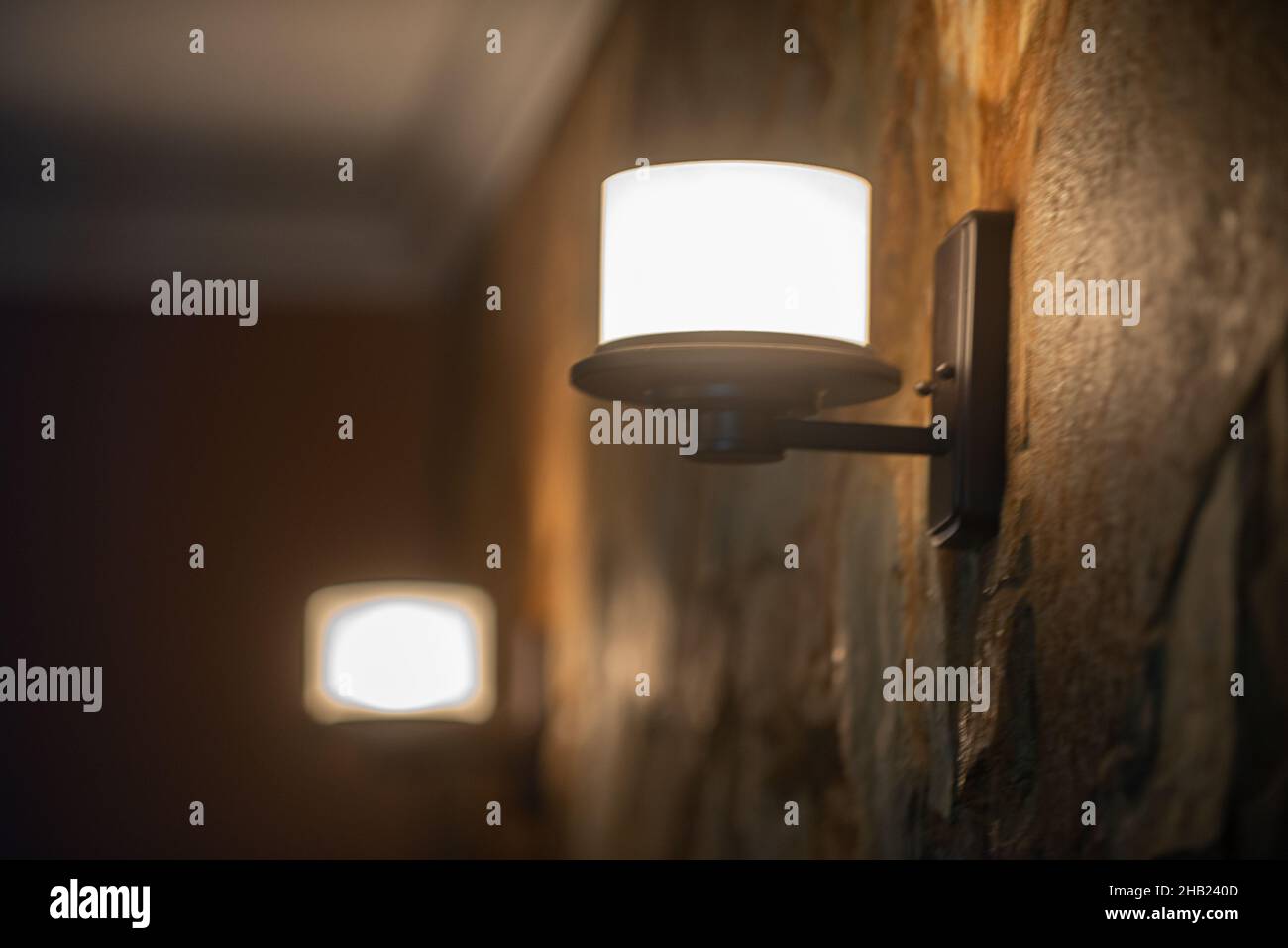 Dimly lit black sconce set mounted on brown stone wall Stock Photo - Alamy
