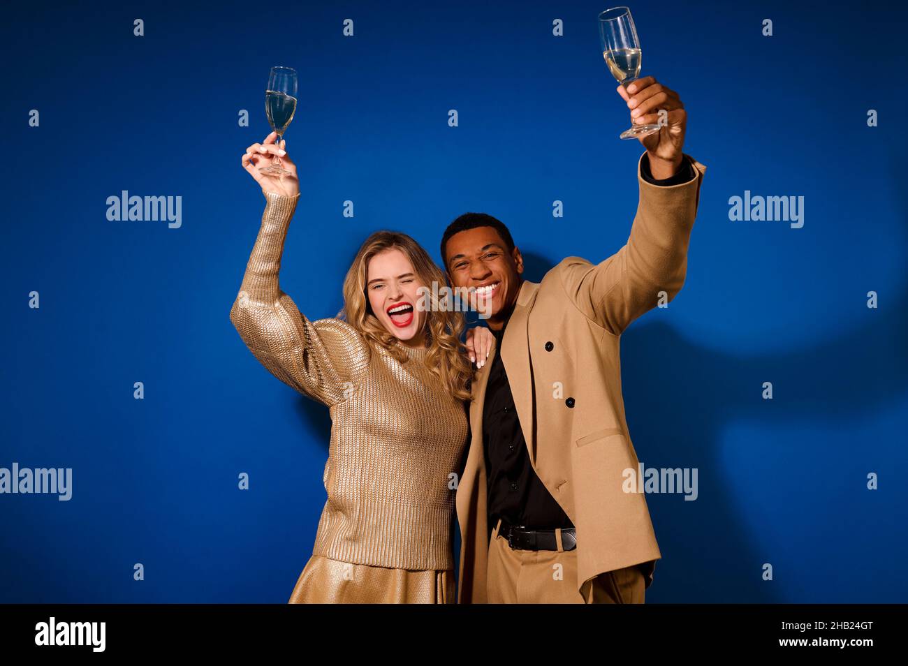 Guy and girl raising glasses looking at camera Stock Photo - Alamy