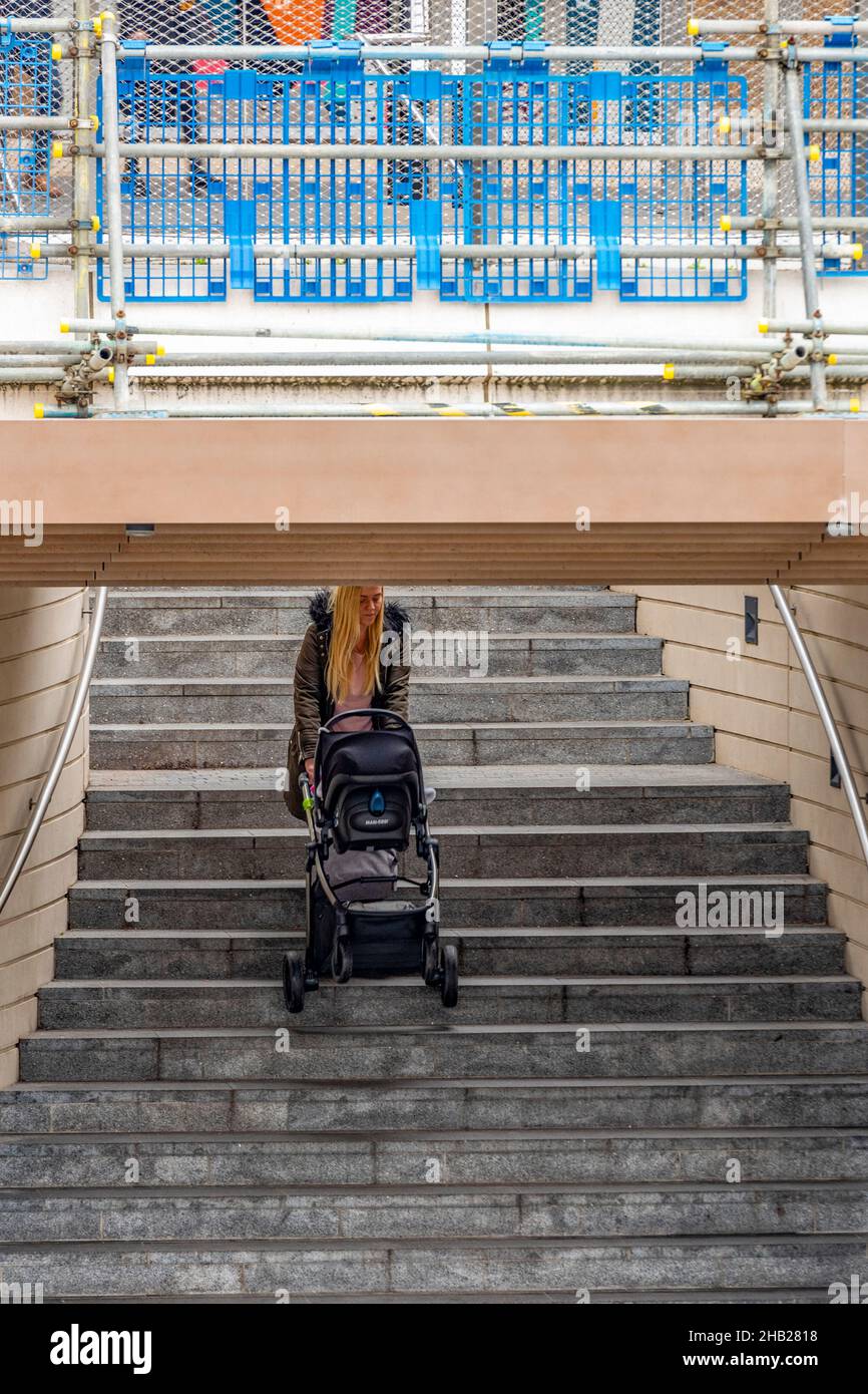 young woman pushing a pushchair or pram down a flight of steps or ...